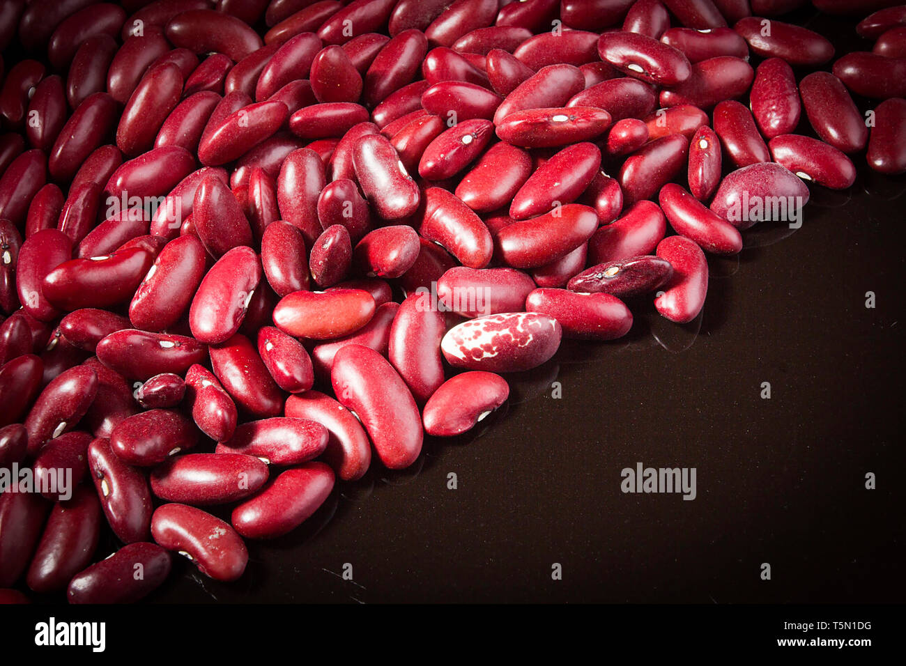 Red beans on a black reflective surface Stock Photo - Alamy