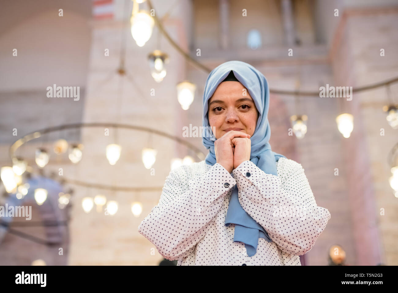 Muslim woman in headscarf and hijab prays while clasping her hands with ...
