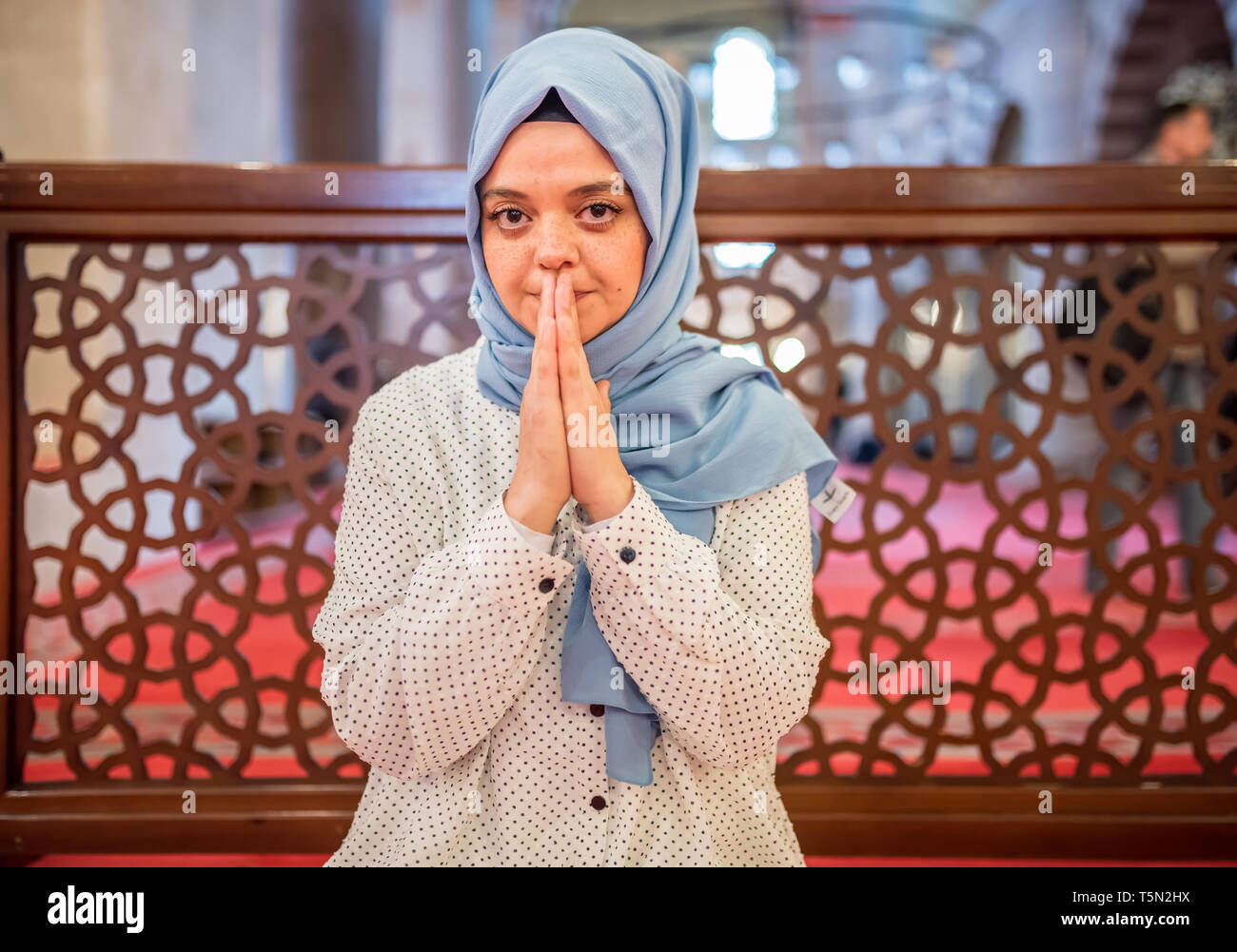 Muslim woman in headscarf and hijab prays while clasping her hands with ...