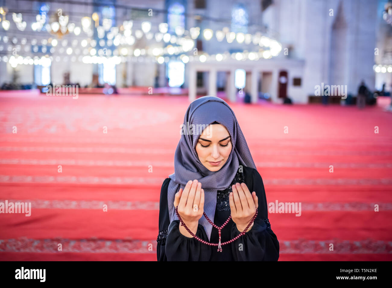 Muslim woman in headscarf and hijab prays with her hands up in air ...