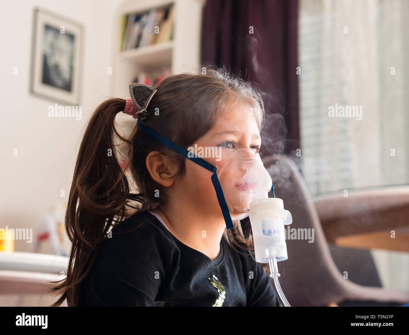 Cute caucasian girl at home taking inhalation from inhaler with oxygen ...