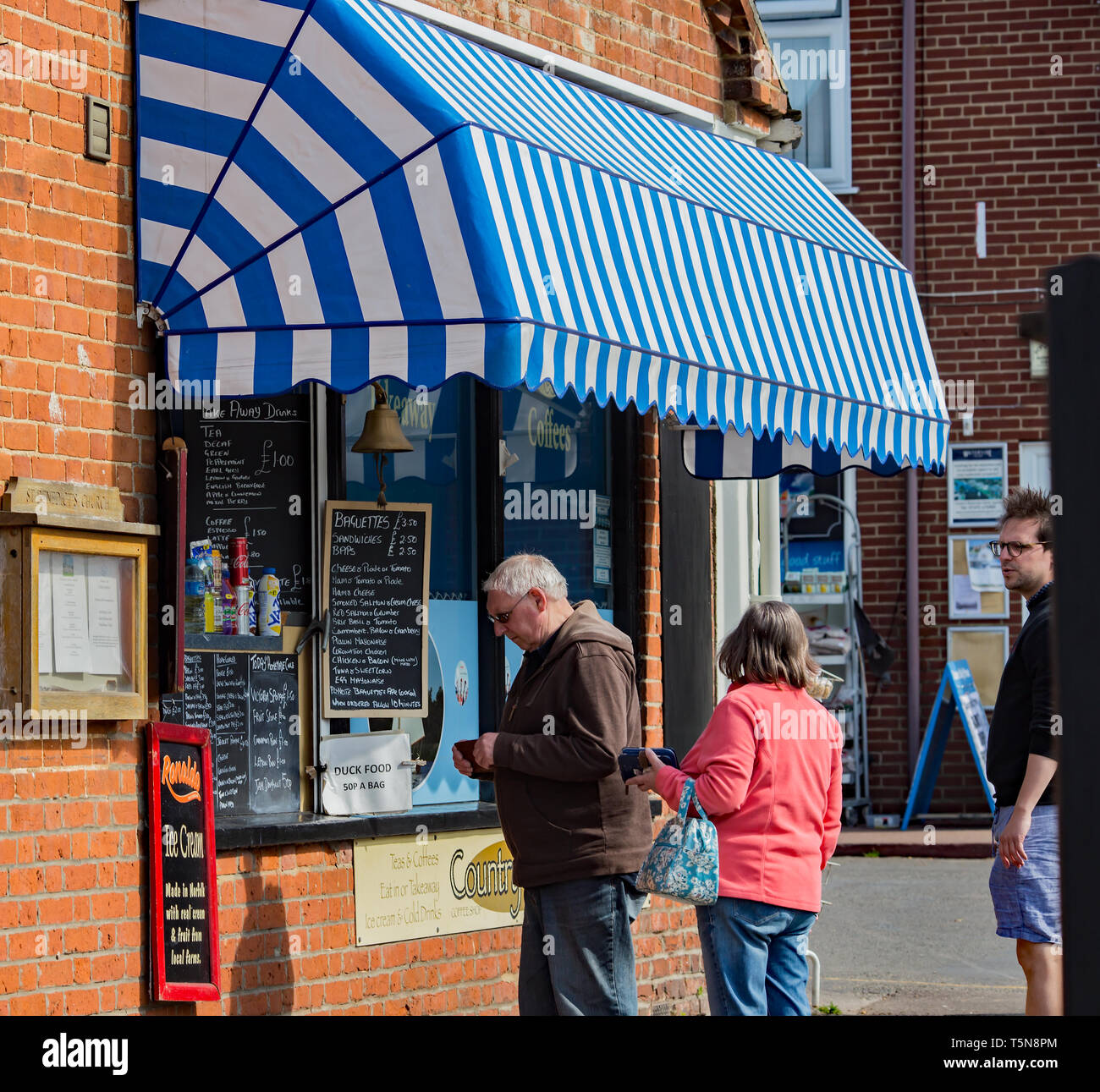 A middle aged man ordering refreshments to take away from a hatch of a ...