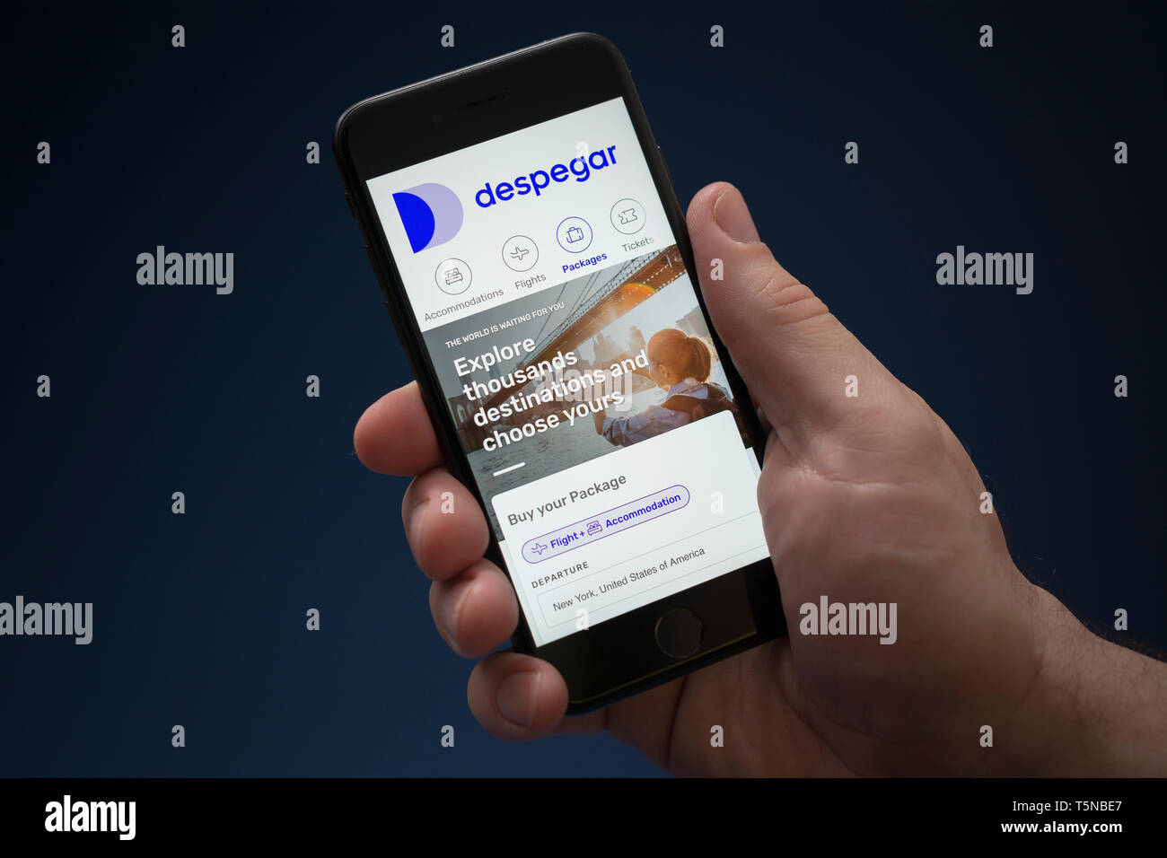 A man looks at his iPhone which displays the Despegar logo (Editorial ...