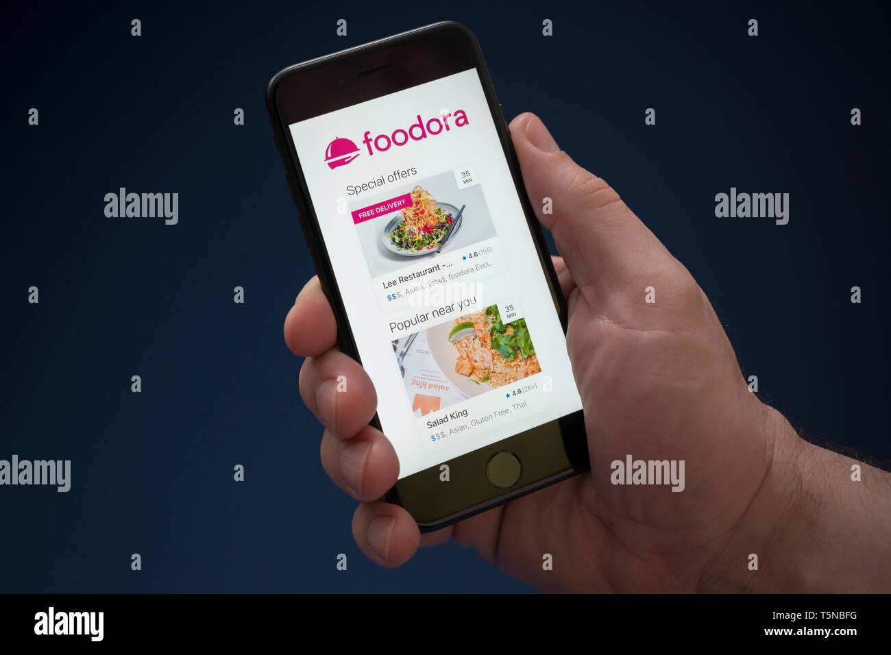 A man looks at his iPhone which displays the Foodora logo (Editorial ...