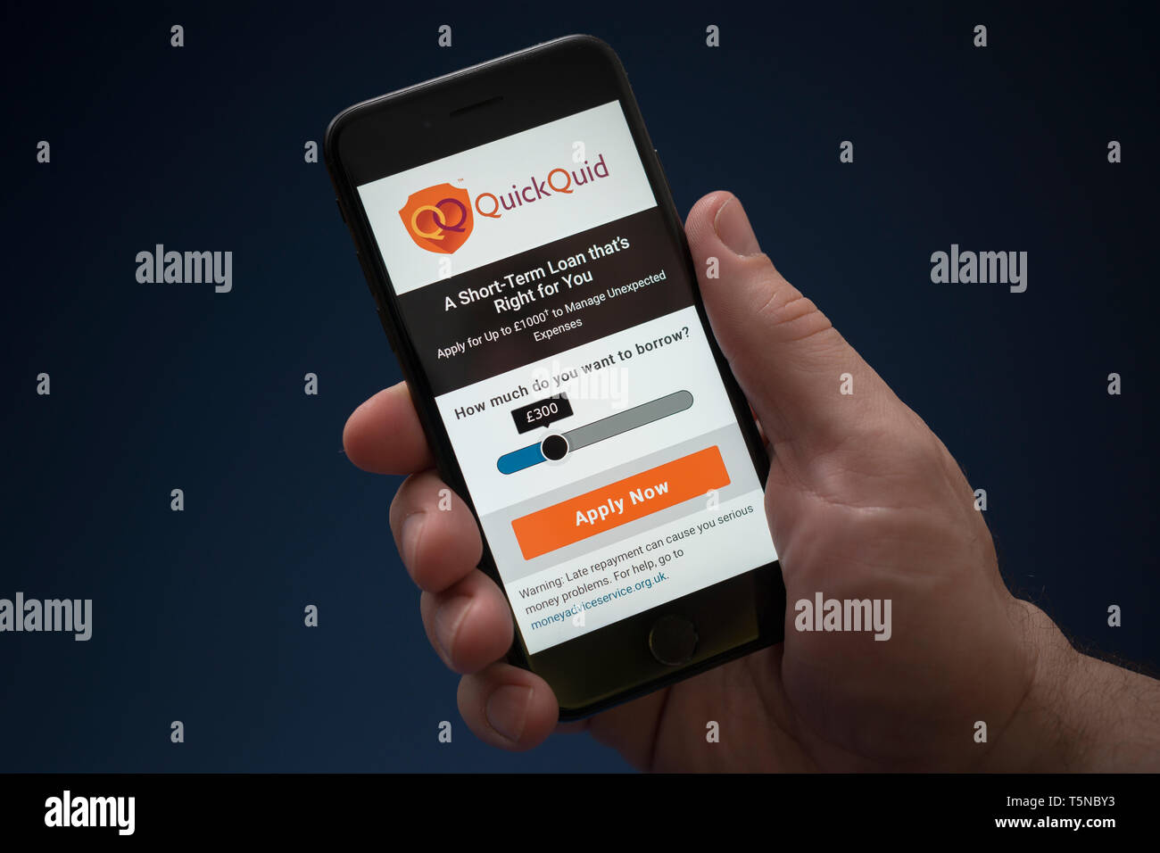 A man looks at his iPhone which displays the Quick Quid logo (Editorial ...