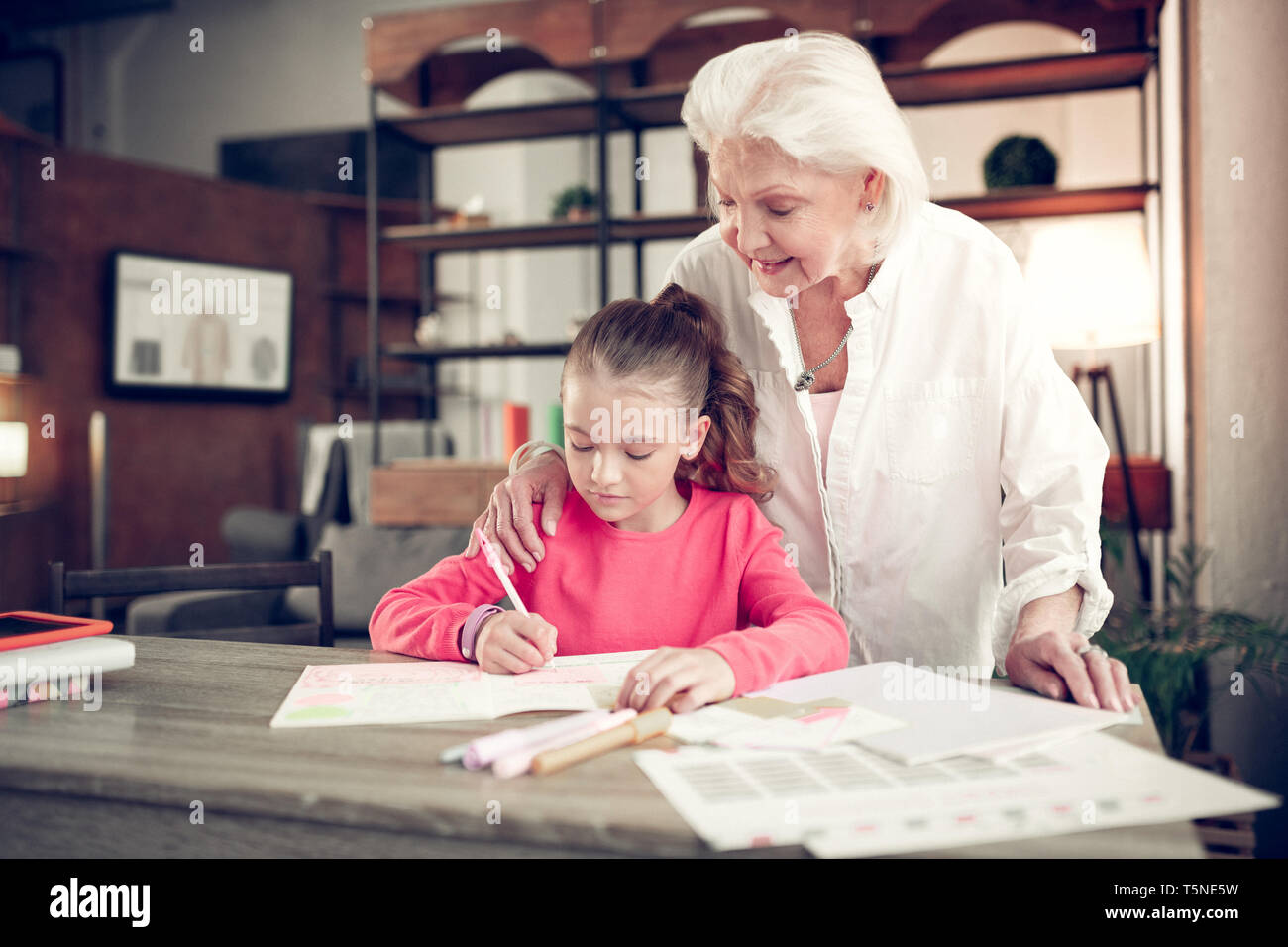 Caring Grey Haired Granny Hugging Her Cute Girl Writing Letters Stock
