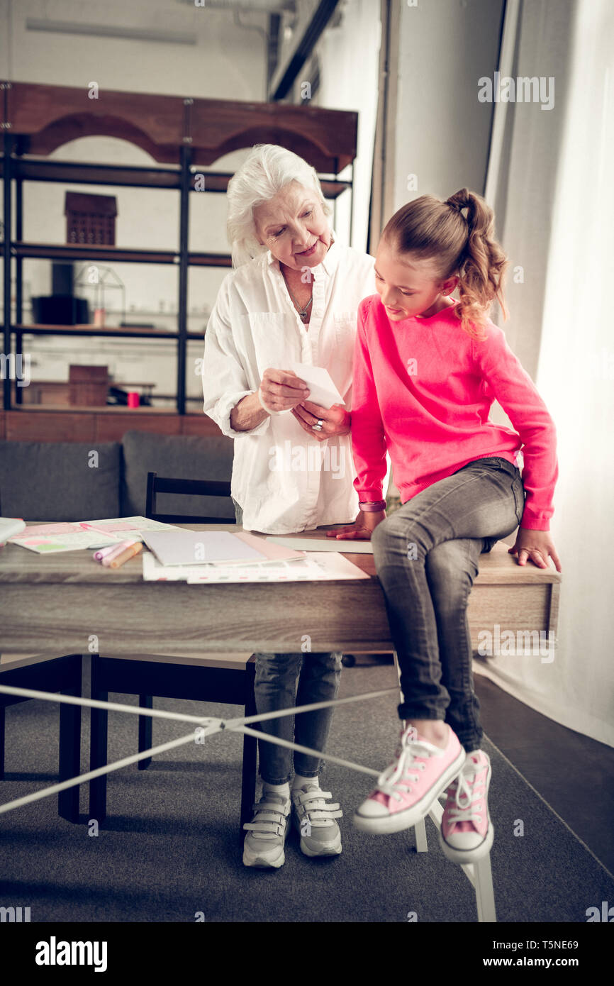 Girl sitting on the table and listening to granny while playing Stock ...