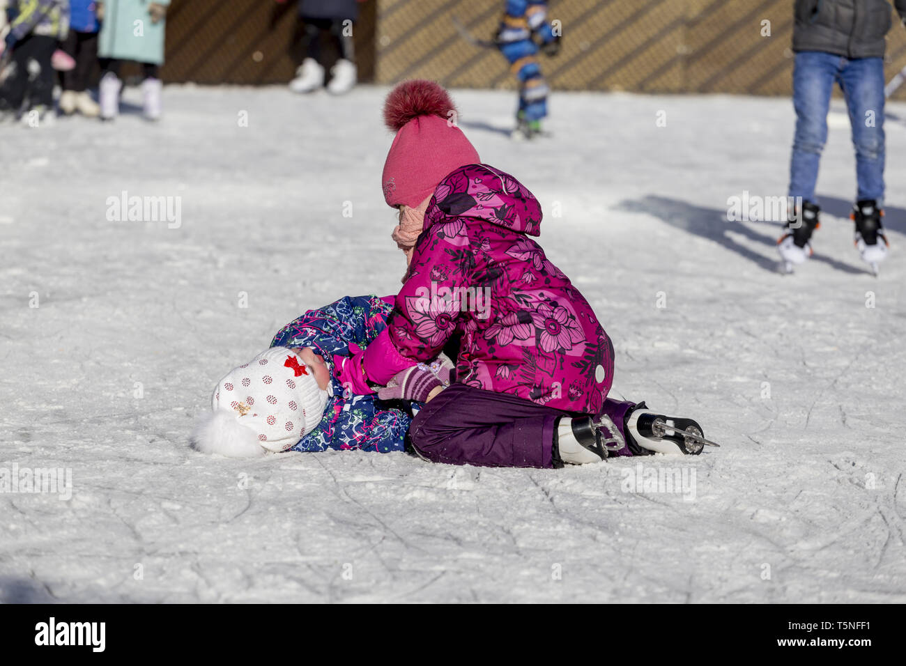 Kids play each other among other children on ice skating rink. Winter ...
