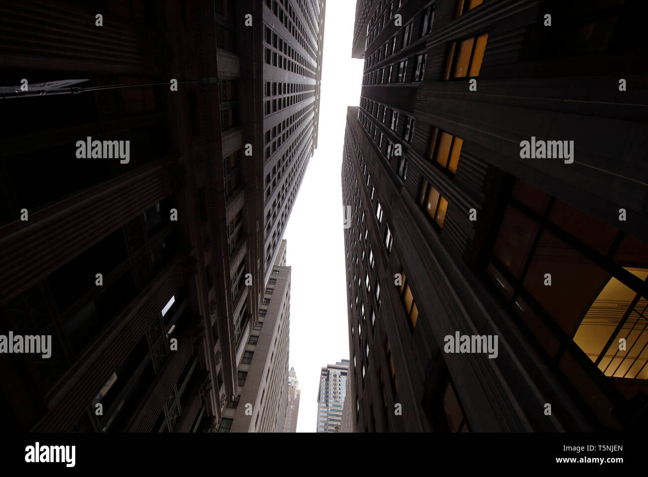 A narrow window of light in between skyscrapers barely illuminates the ...