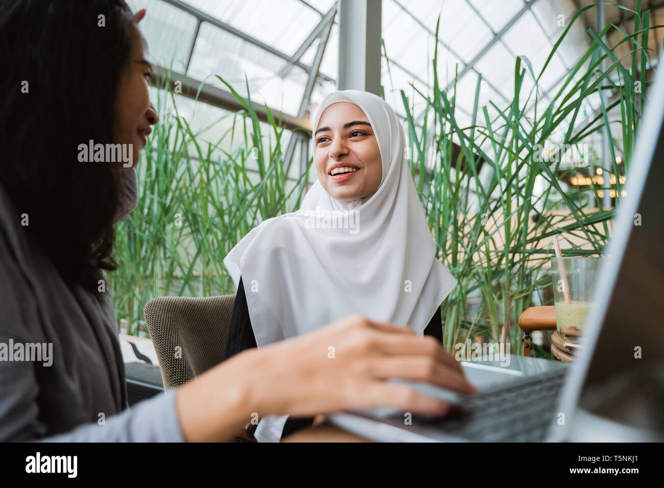muslim woman and friend discussing with laptop Stock Photo - Alamy