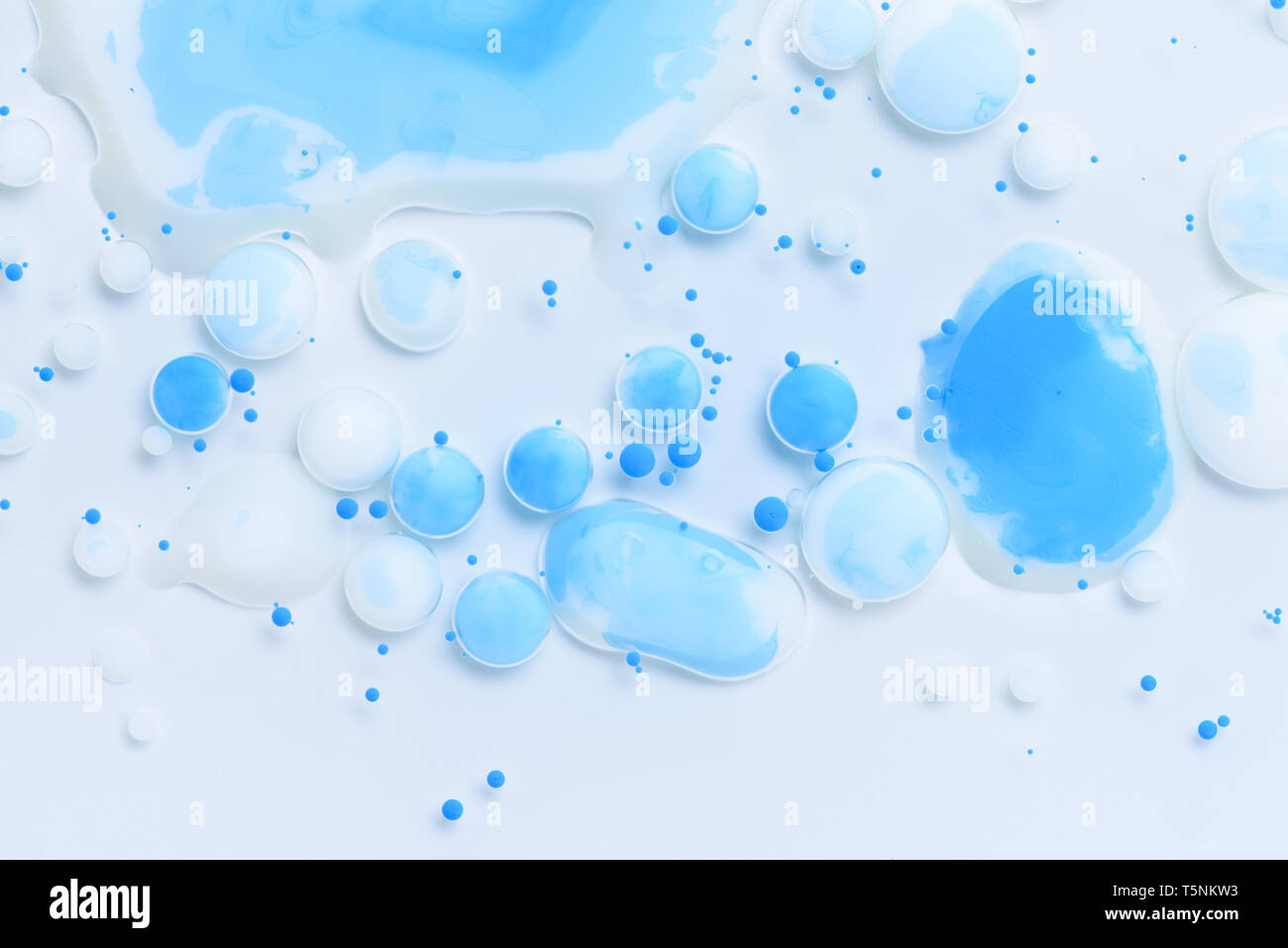 Abstract background with white and mixed blue paint drops in liquid ...