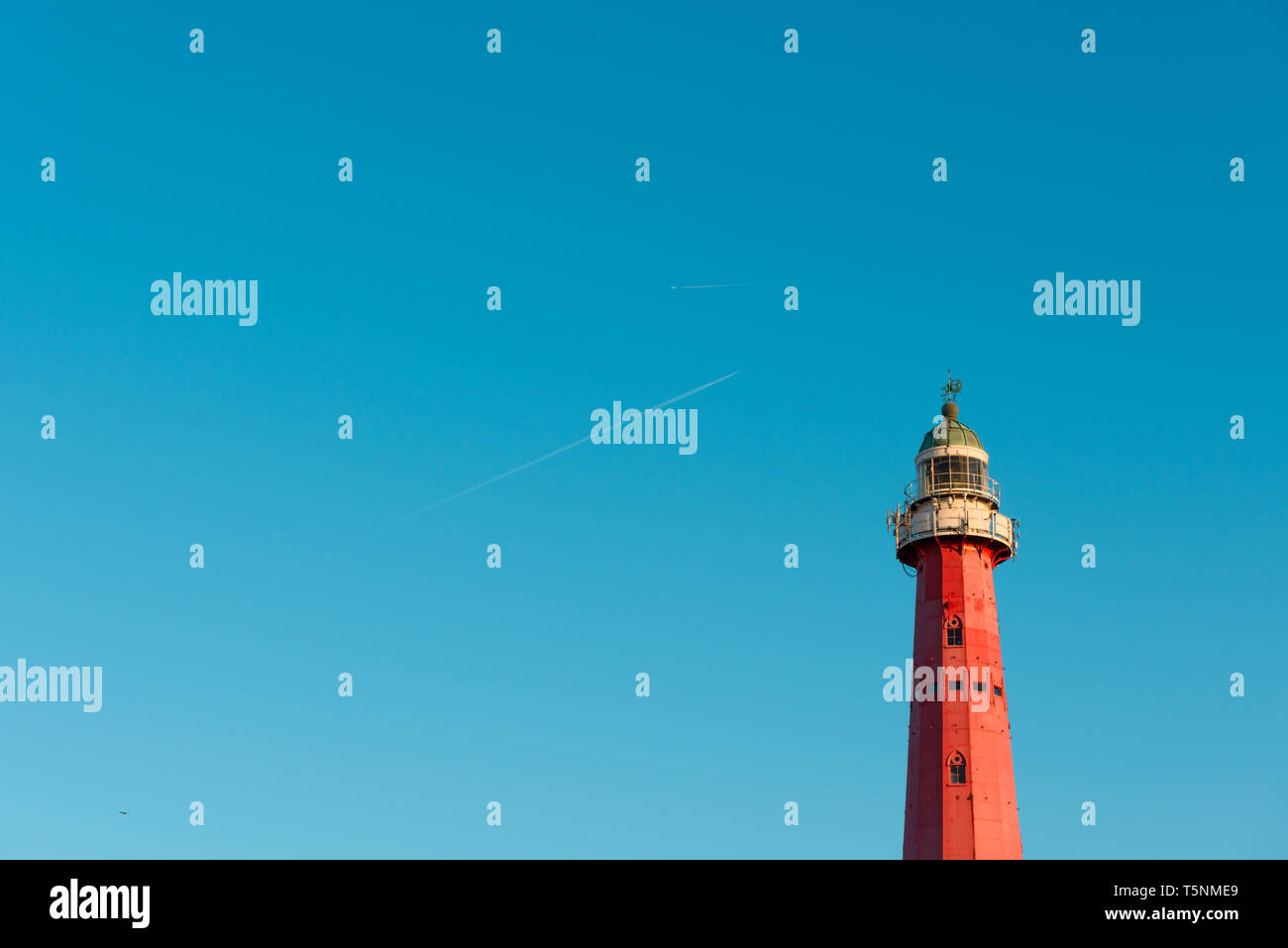 Lighthouse over blue sky background with airplane traces and copy space ...