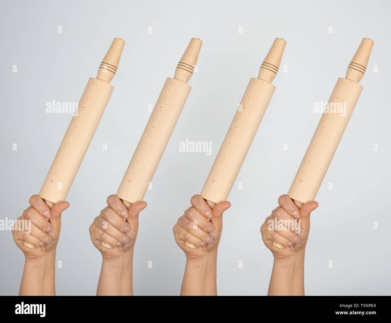 hands hold kitchen wooden rolling pins on gray background, part of the ...