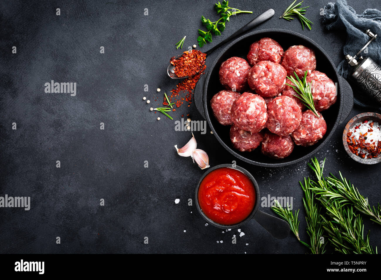 Fresh raw beef meatballs with spices and tomato sauce Stock Photo - Alamy
