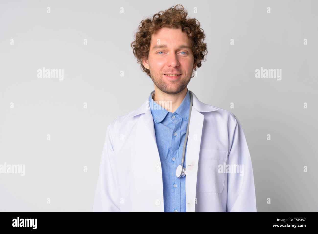 Happy handsome man doctor with curly hair smiling Stock Photo - Alamy
