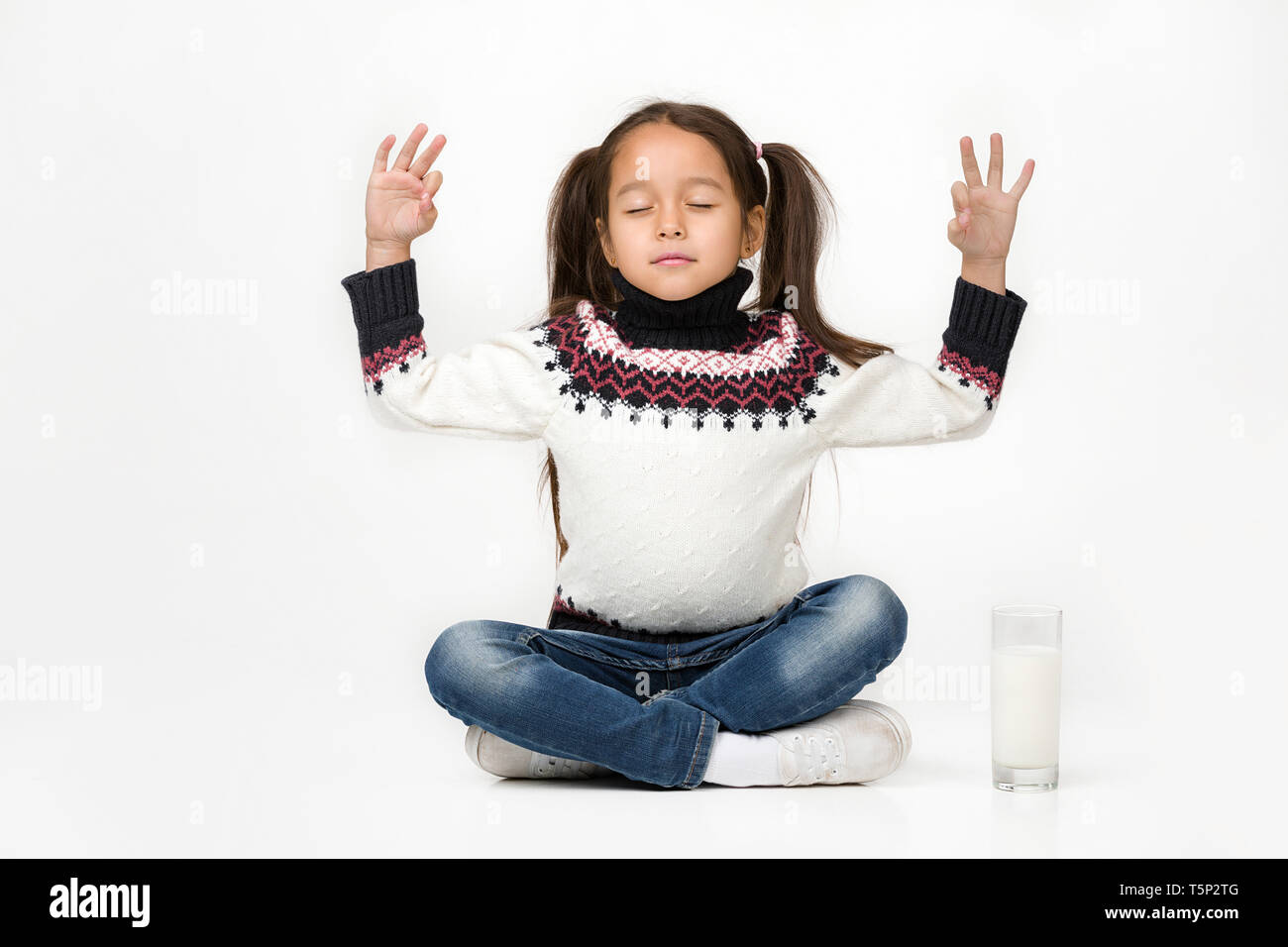 Portrait of cute little child girl sitting in lotus position and a ...