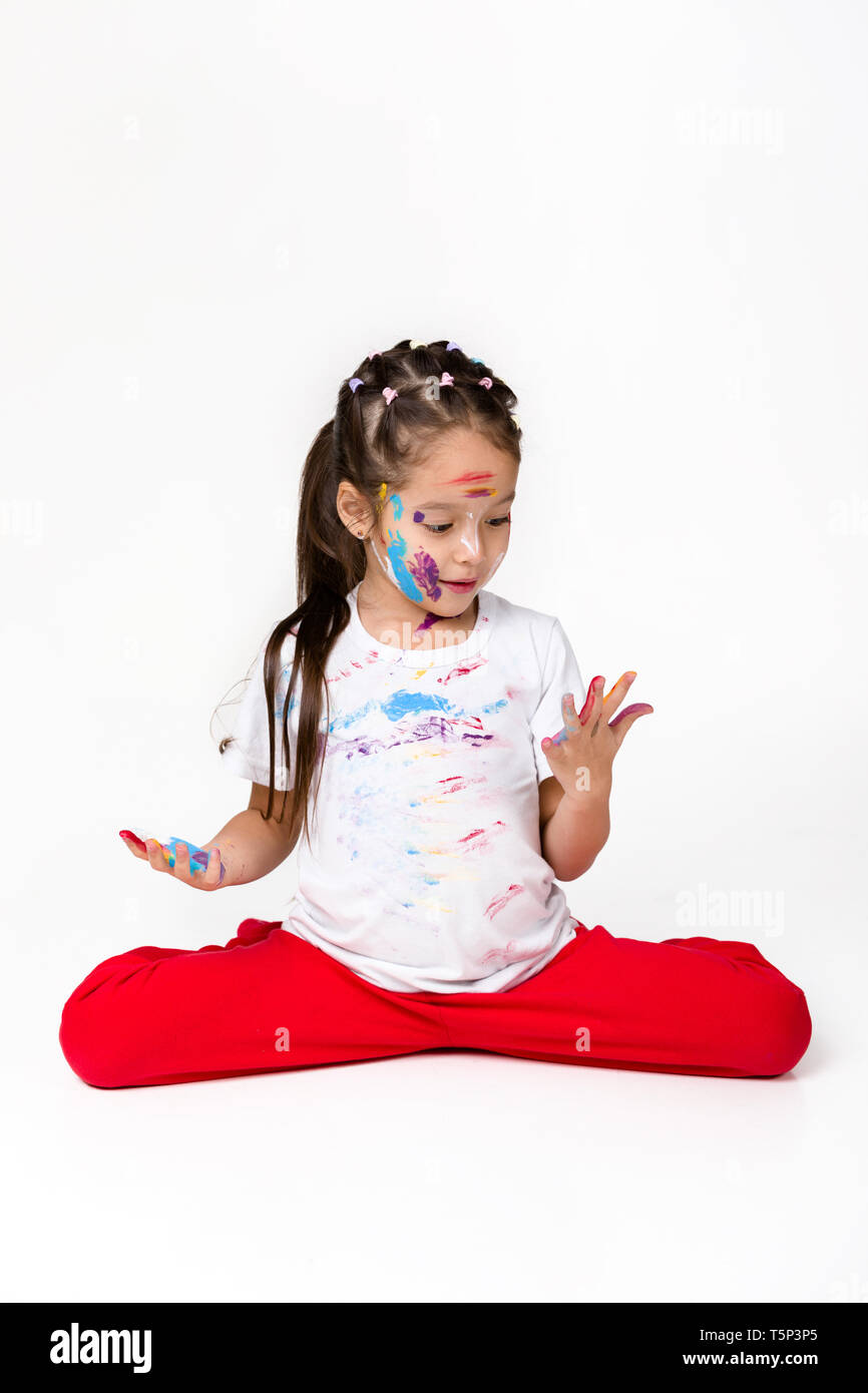 scared little child girl looks at his hands painted in colorful paint ...