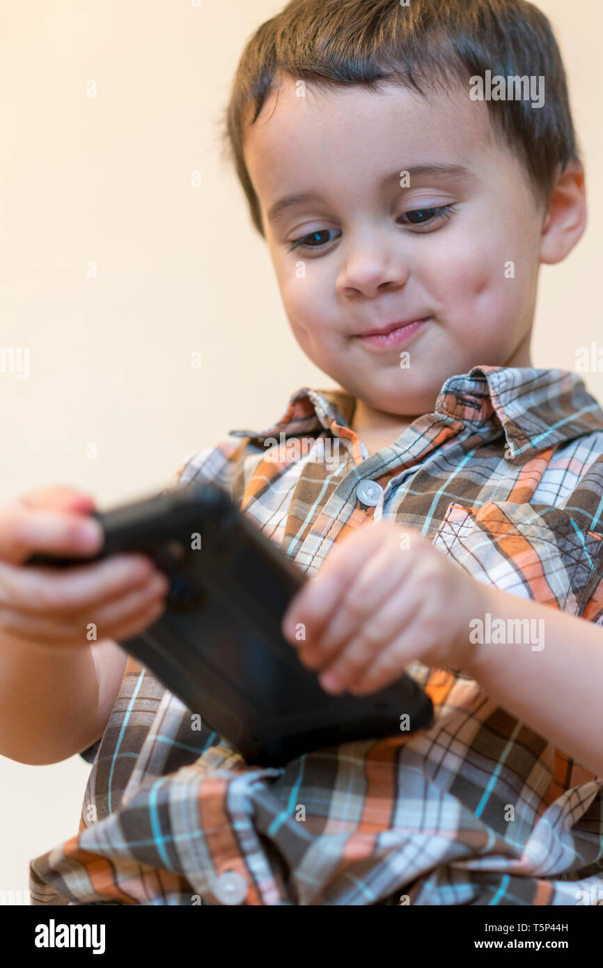 Portrait of a smiling little boy holding mobile phone isolated over ...