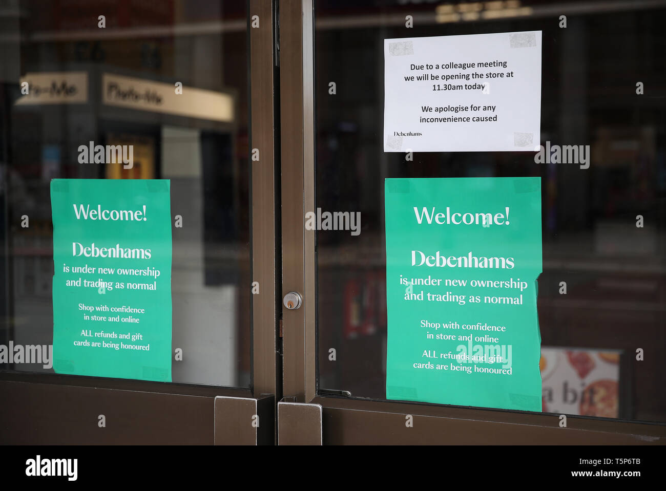 A sign apologising for opening late on the door the Debenhams ...