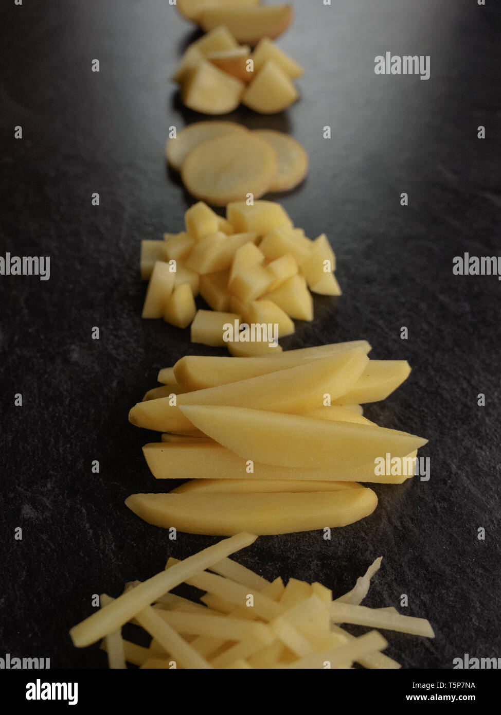 Different cuts of potatoes on a black textured background. Photo taken ...