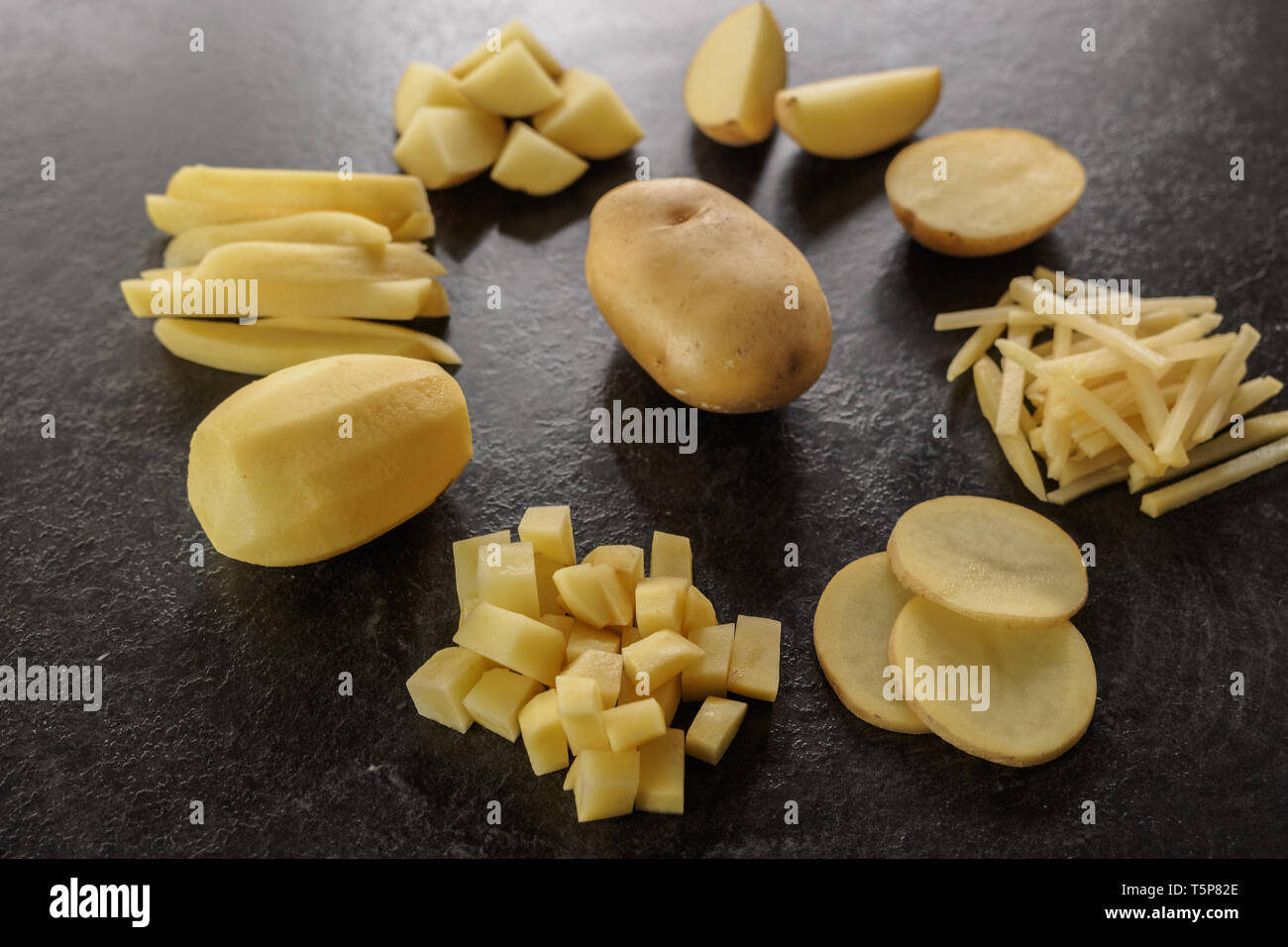 Different cuts of potatoes on a black textured background. Photo taken ...