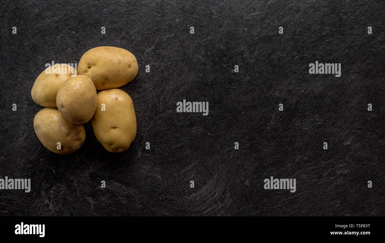 Different cuts of potatoes on a black textured background. Photo taken ...