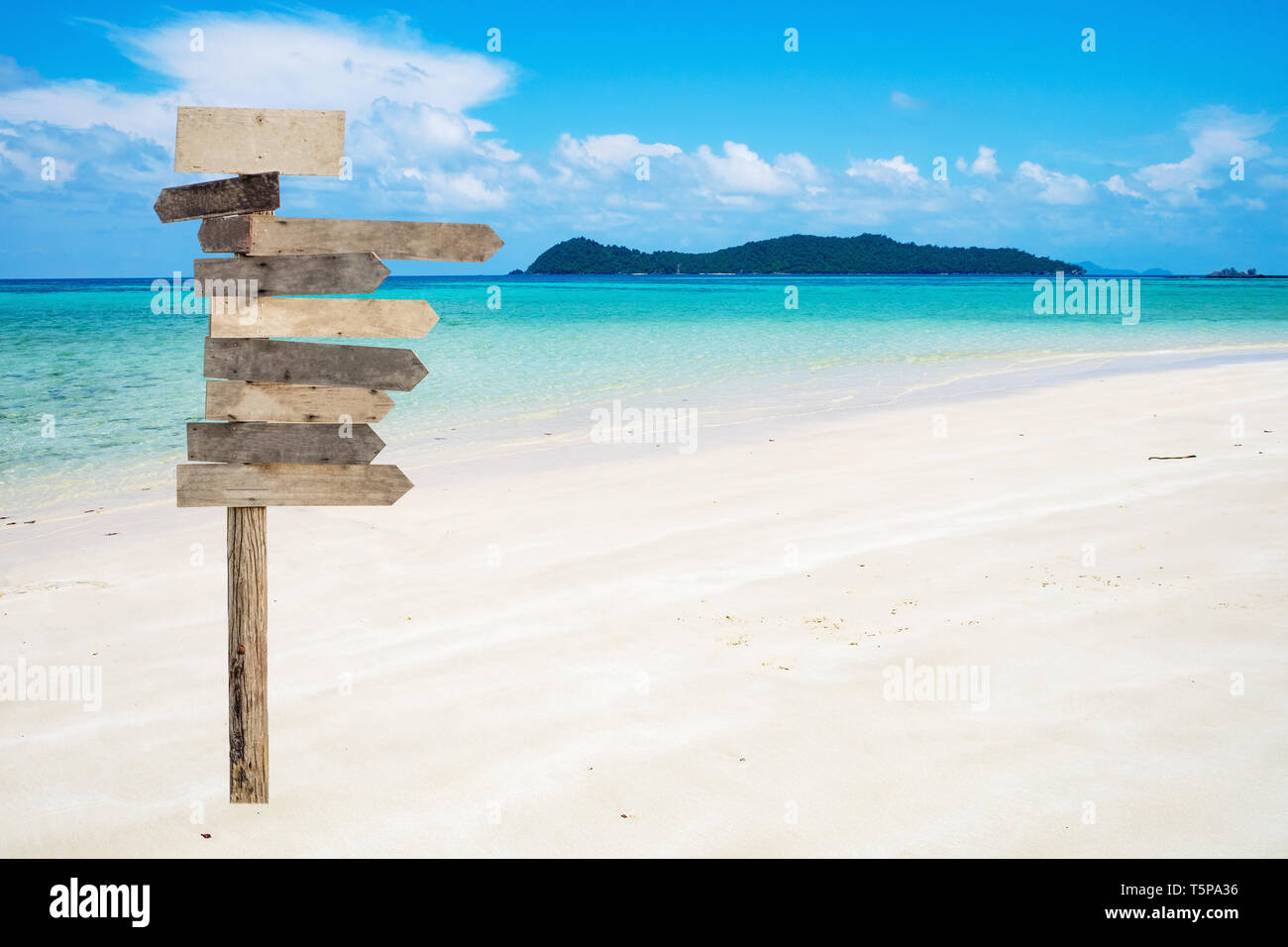 Wooden arrows signboard on beautiful tropical sea with white beach ...