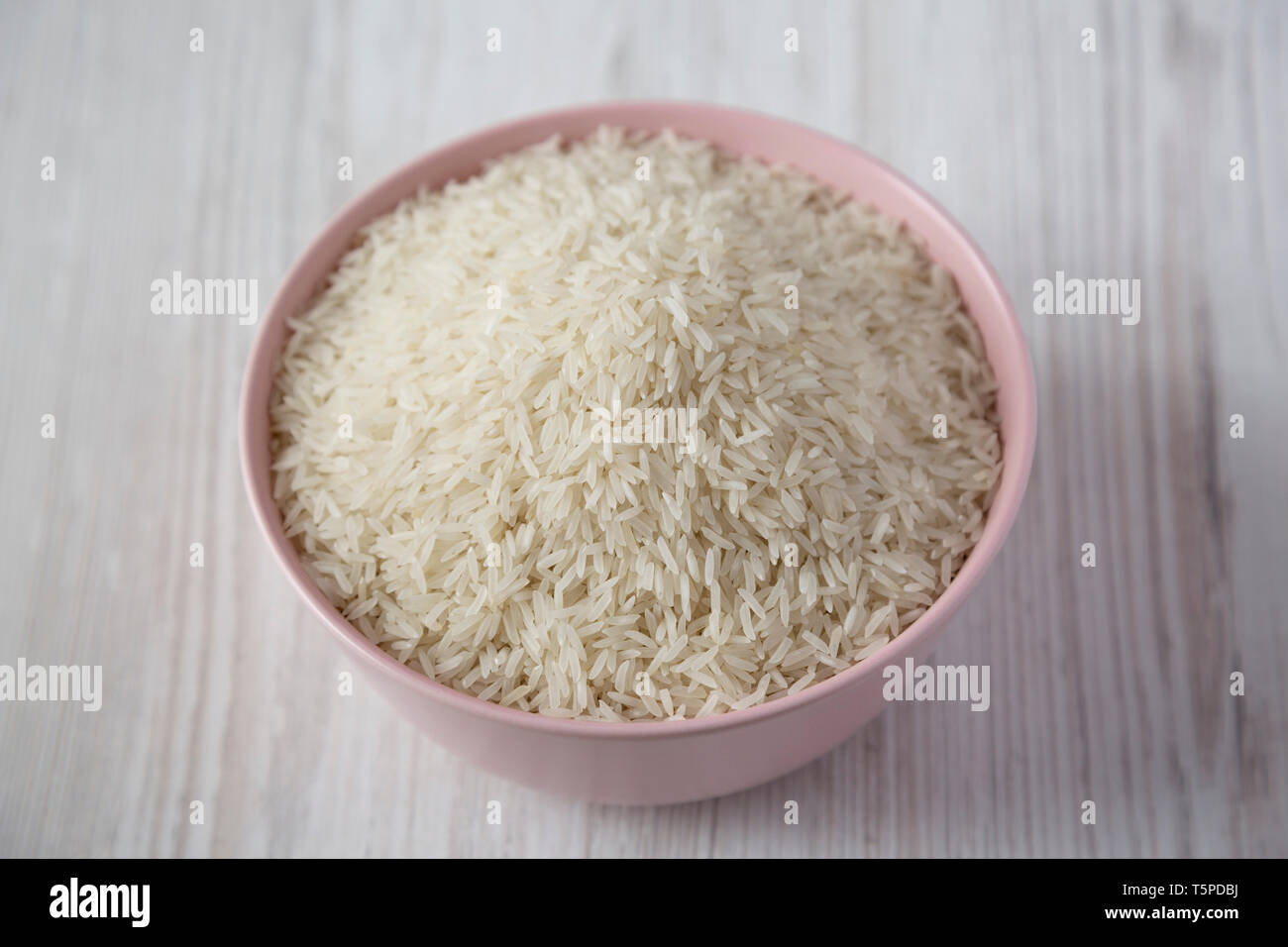 Dry white rice basmati in a pink bowl over white wooden background ...