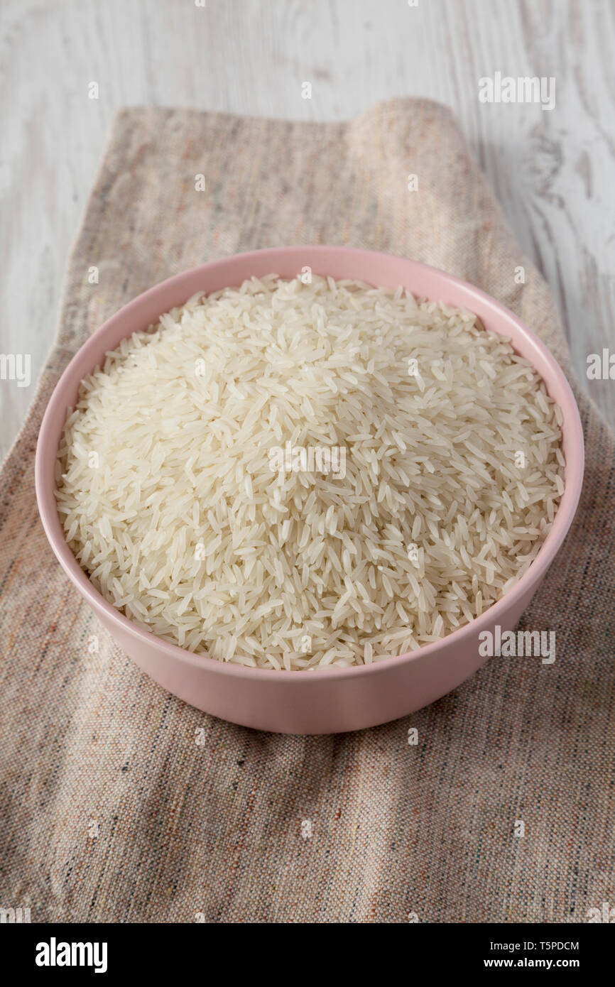Dry white rice basmati in a pink bowl over white wooden background ...