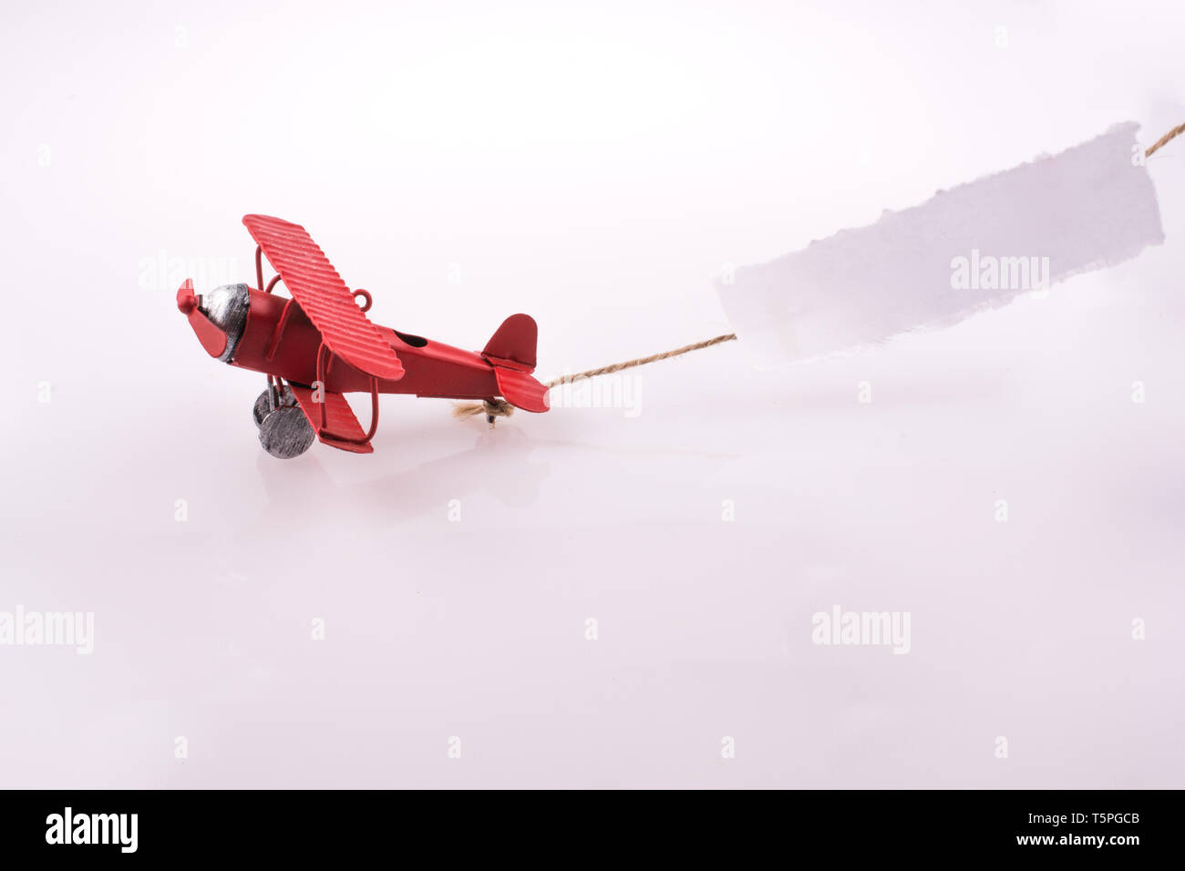 Red plane flying with a paper after it on a white background Stock ...