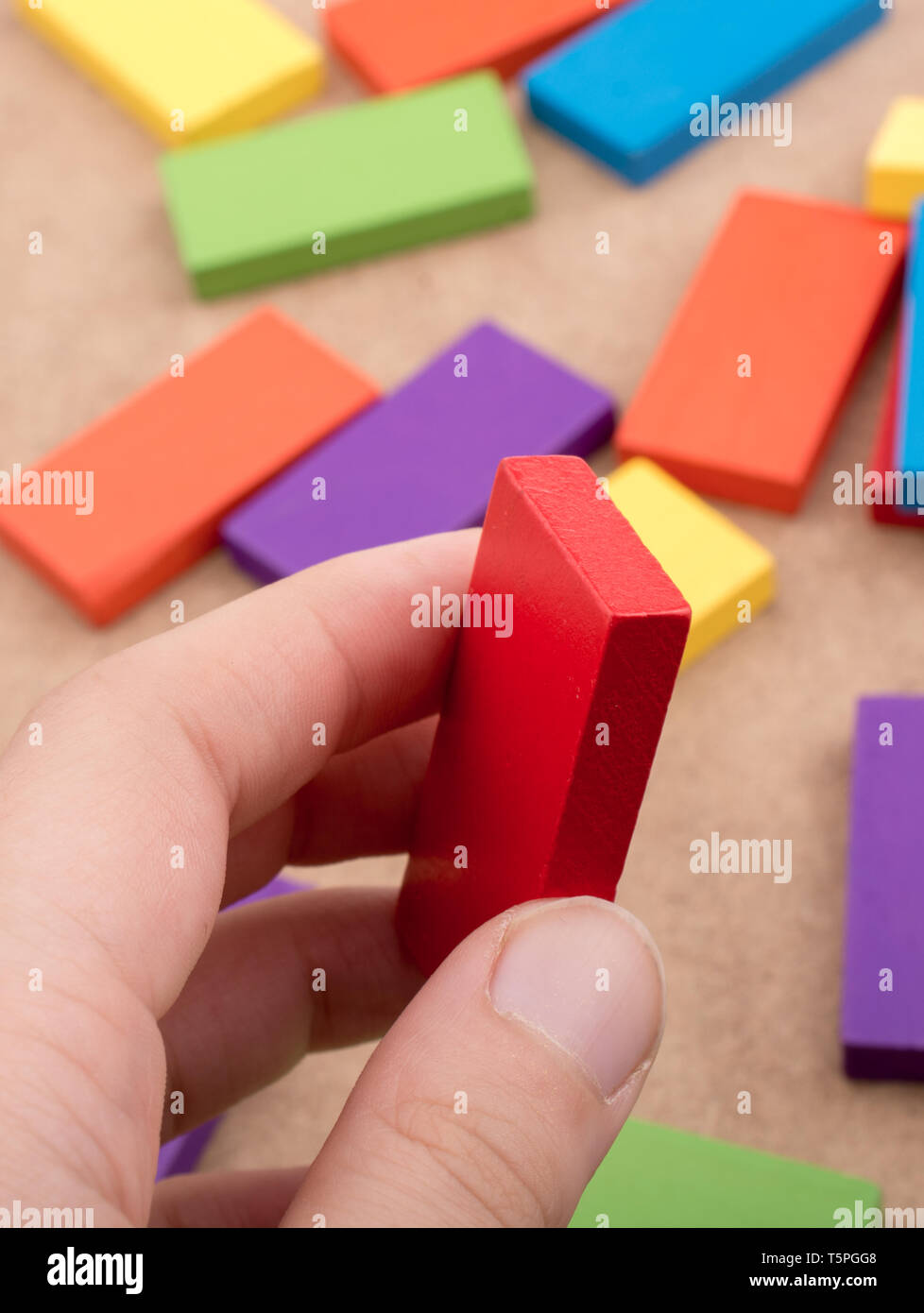 Hand holding one of the wooden blocks of various colors Stock Photo - Alamy