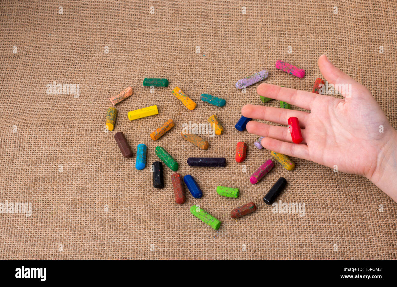 Hand holding a crayon by crayons forming a heart shape Stock Photo - Alamy