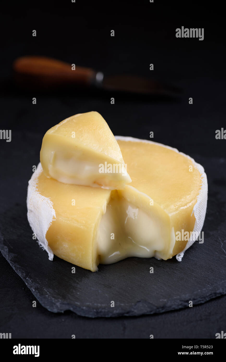 Soft round cheese on slate background with one piece cut Stock Photo ...