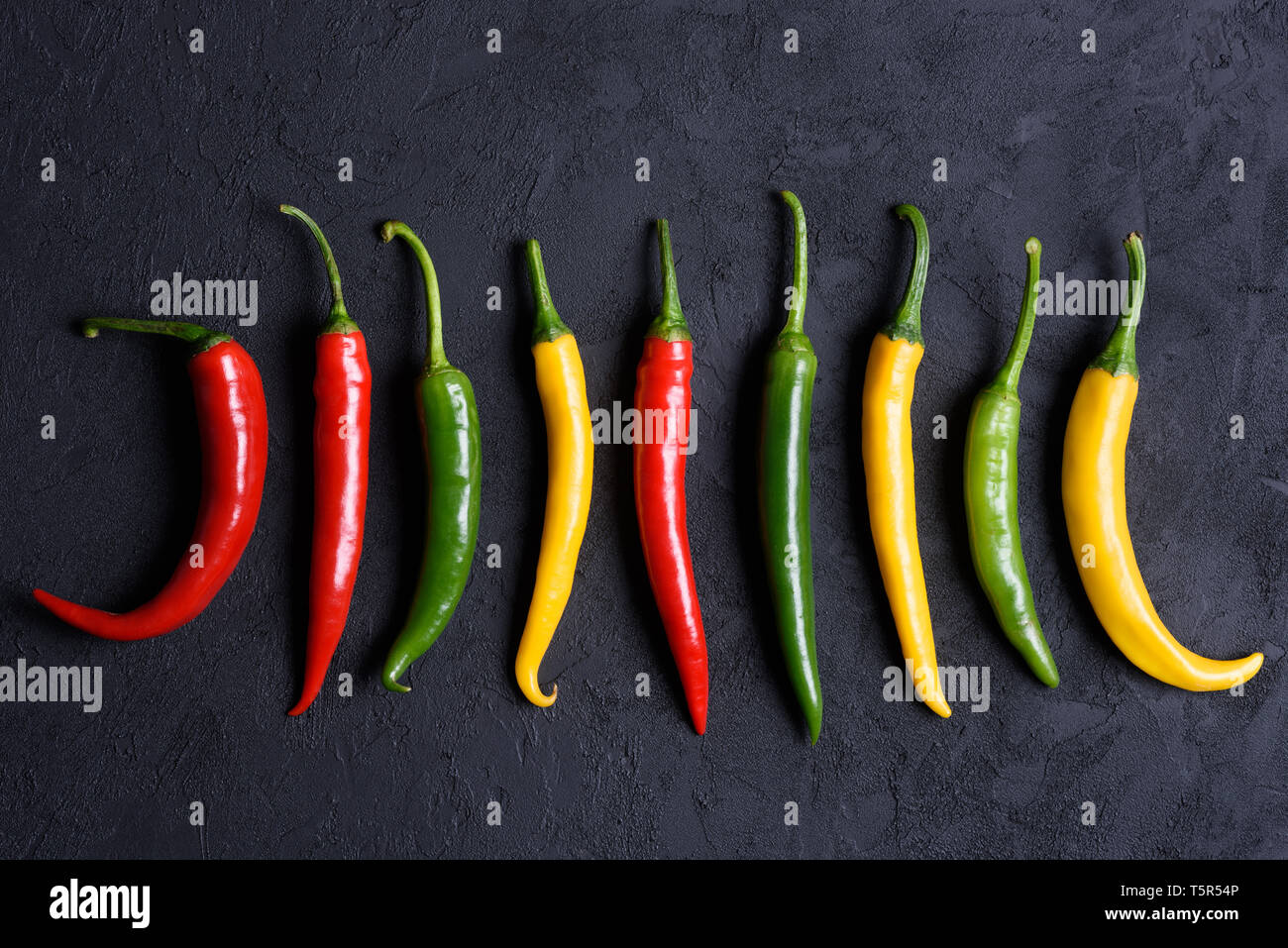 Different colored chilli peppers on dark background Stock Photo - Alamy