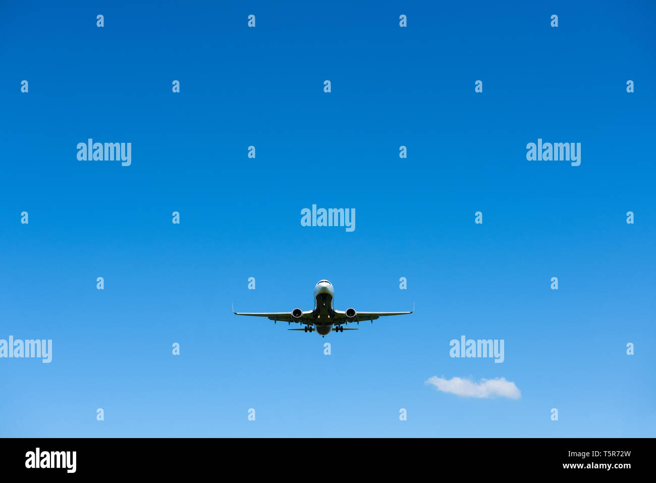 Airplane in the clear blue sky, preparing to landing, front view from ...