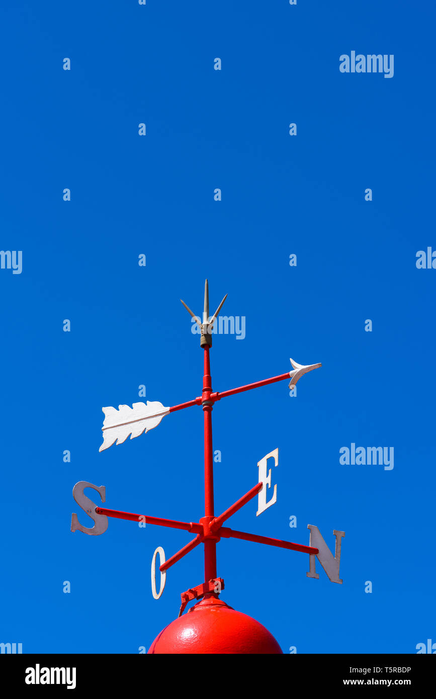 Vintage red and white painted metal wind vane with arrow over blue ...