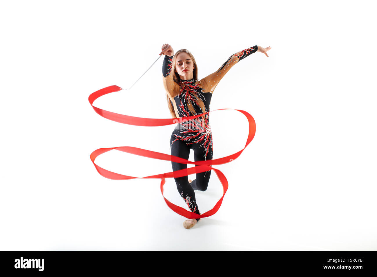 Rhythmic gymnastics. Young gymnast girl with red ribbon on white ...