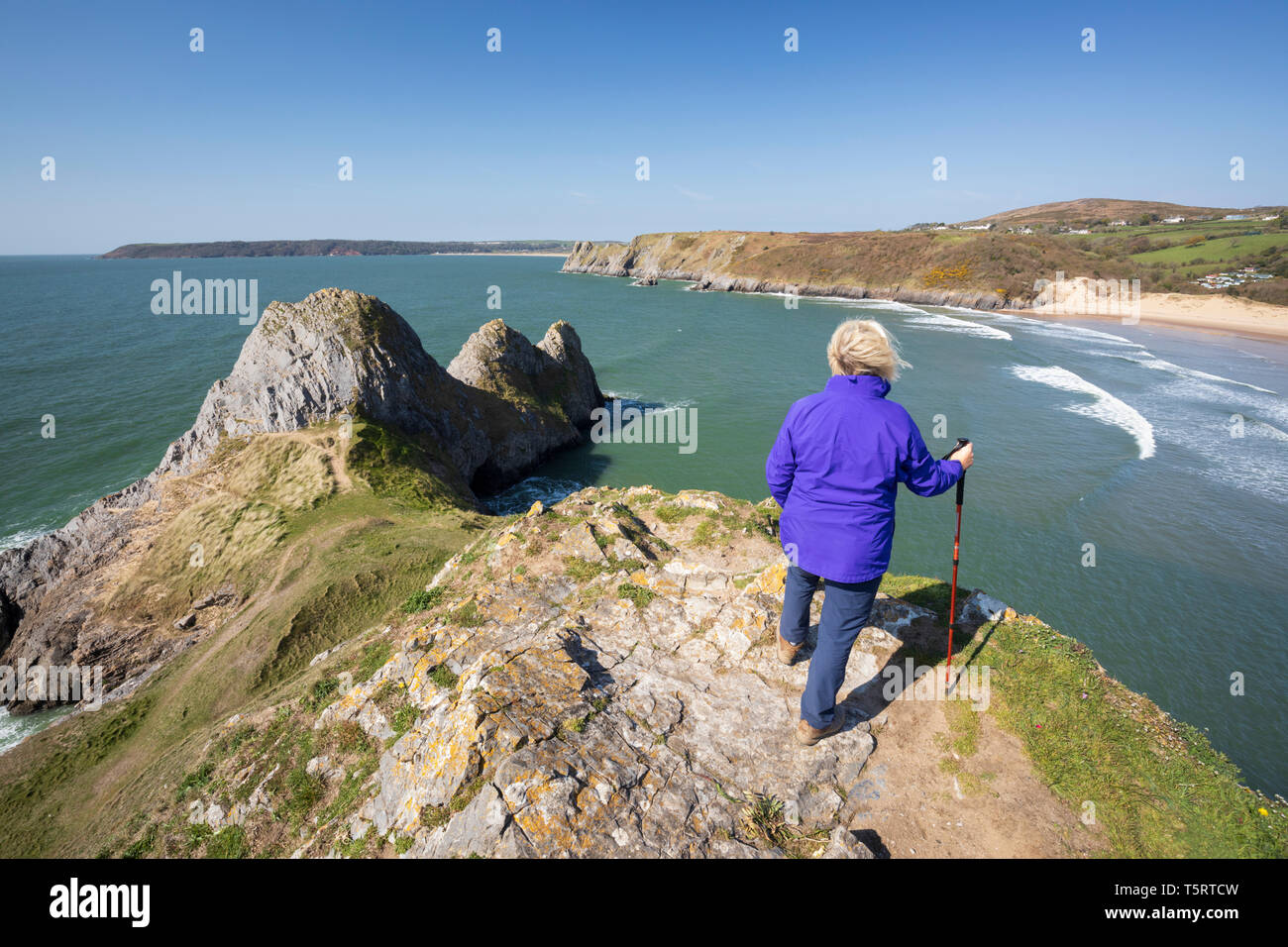 Walker standing above the Three Cliffs Bay at high tide, Gower ...