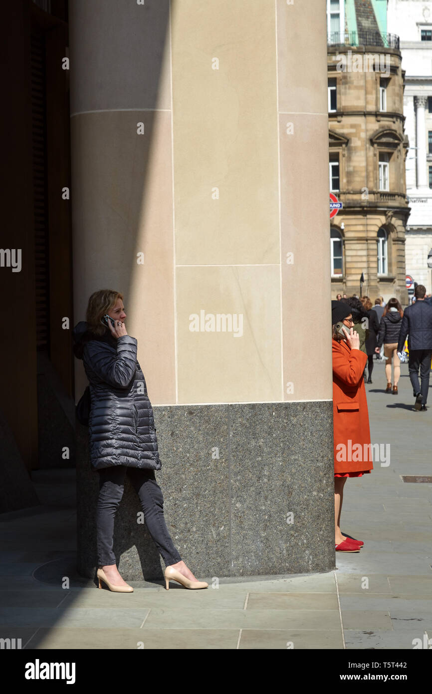 Two women using mobile phones in the City of London Stock Photo - Alamy