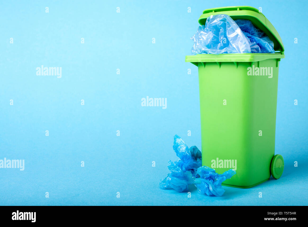 Green dustbin on a blue background. Polyethylene. Recycling. Materials ...