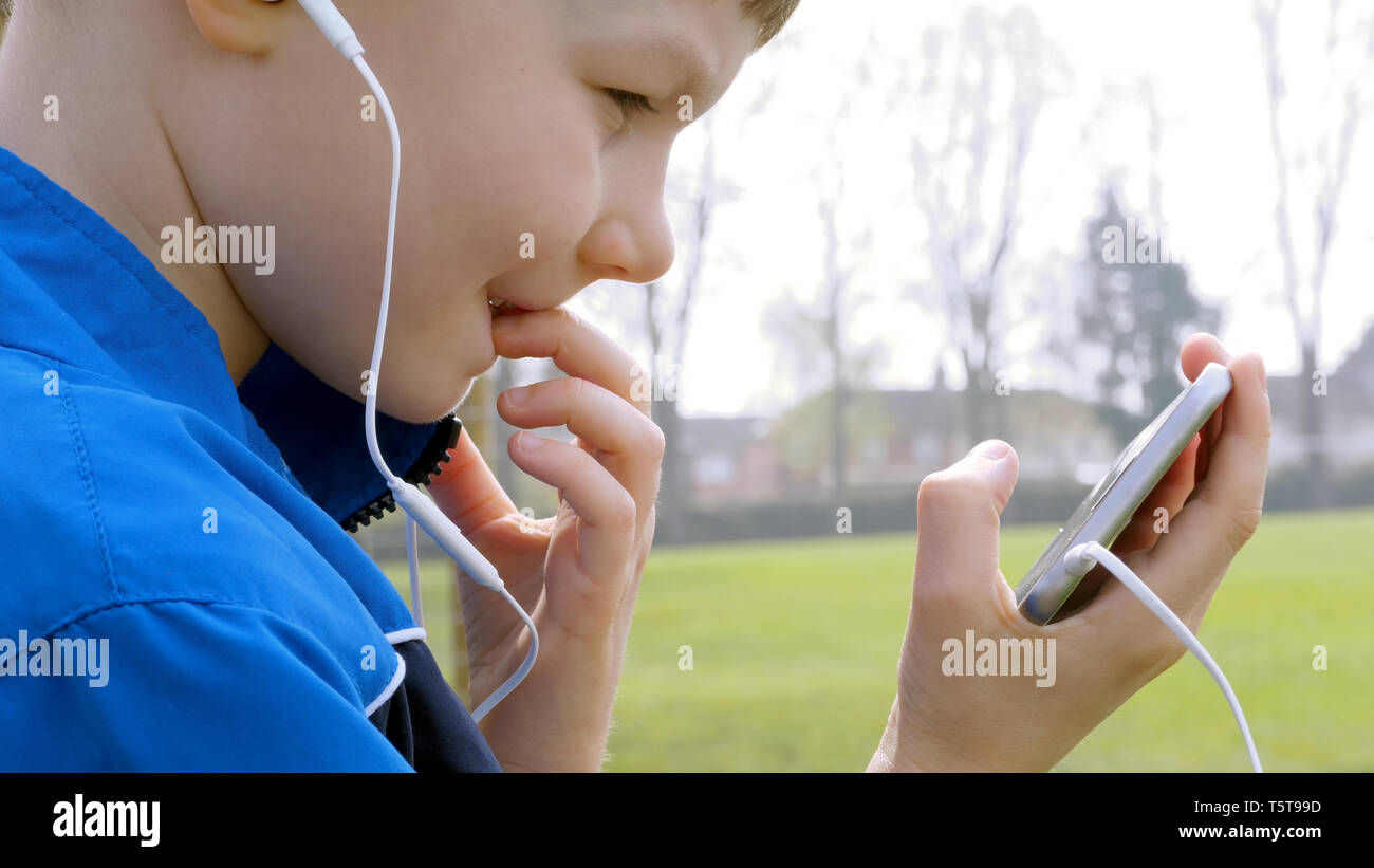 curious teen boy with smart phone listening or talking while sitting in ...