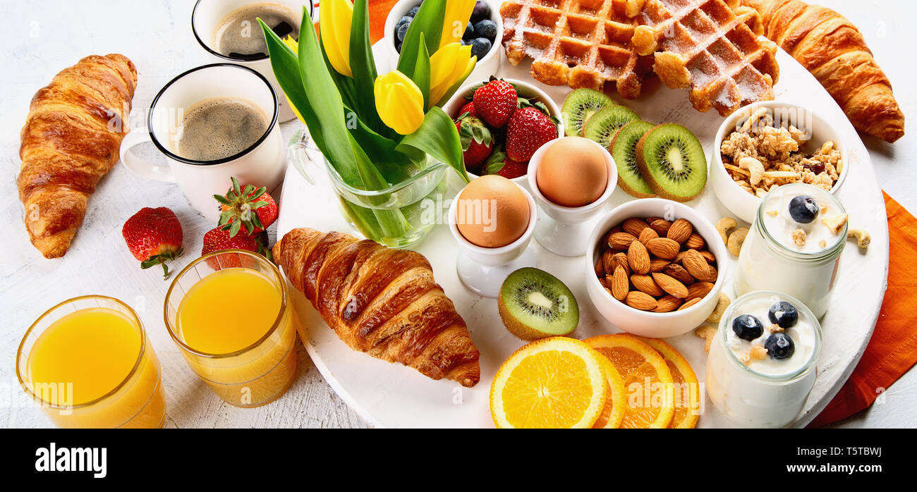 Breakfast table with eggs, berries, yogurt,waffle and croissant ...