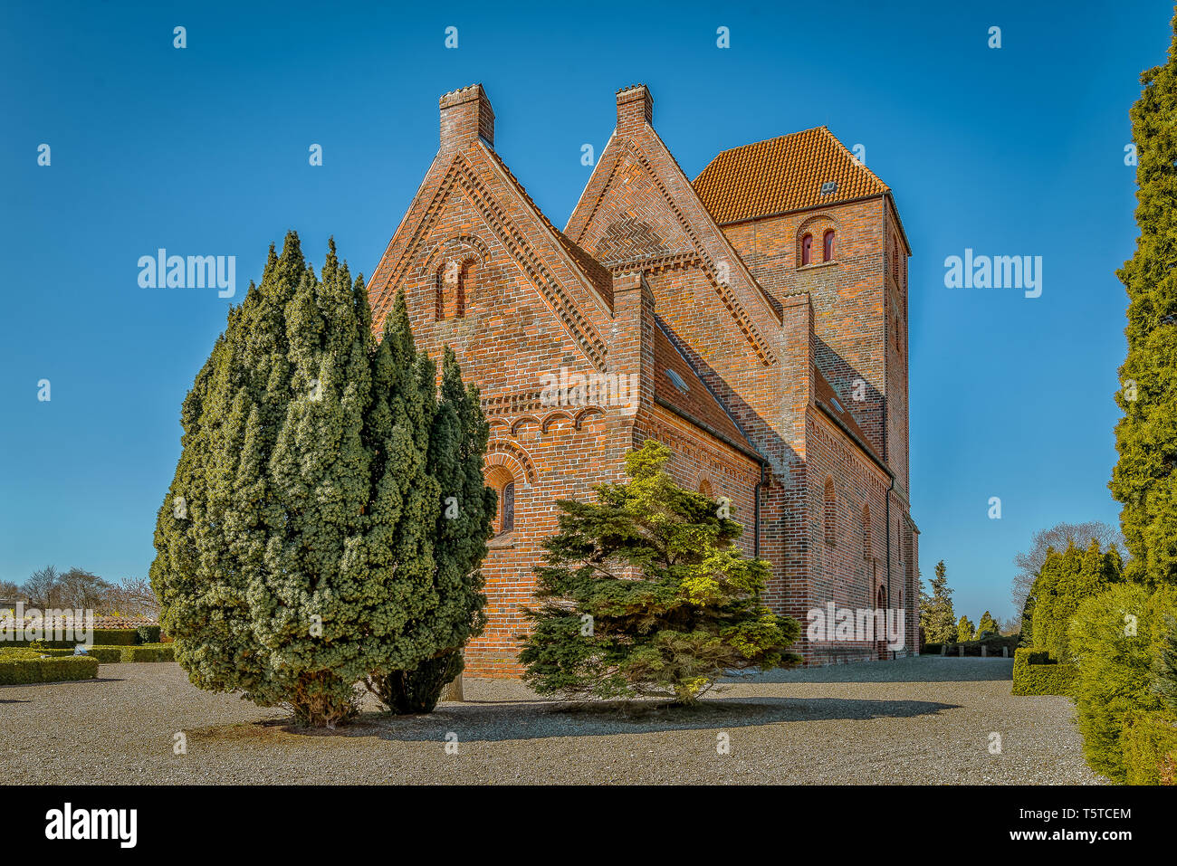 Medieval danish brick church with blue sky and green trees, Tirsted ...