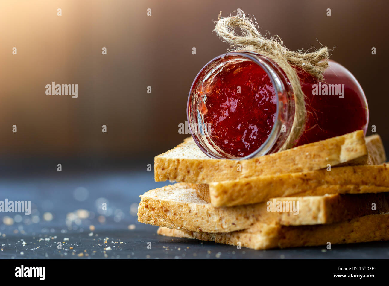 Strawberry jam bottle and whole wheat bread are stacked on a black ...