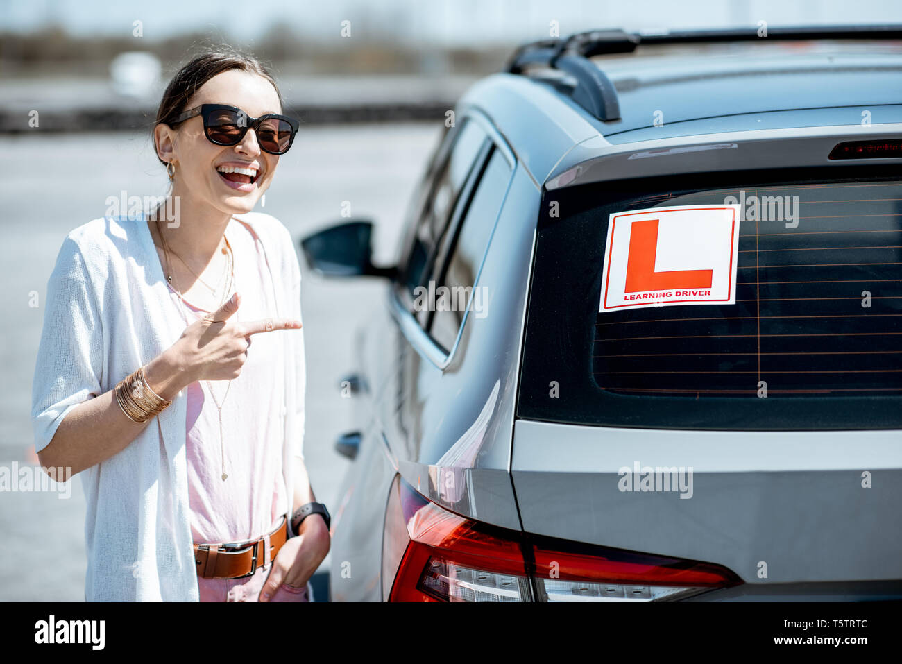 Portrait of a young female student standing near the learning car on ...
