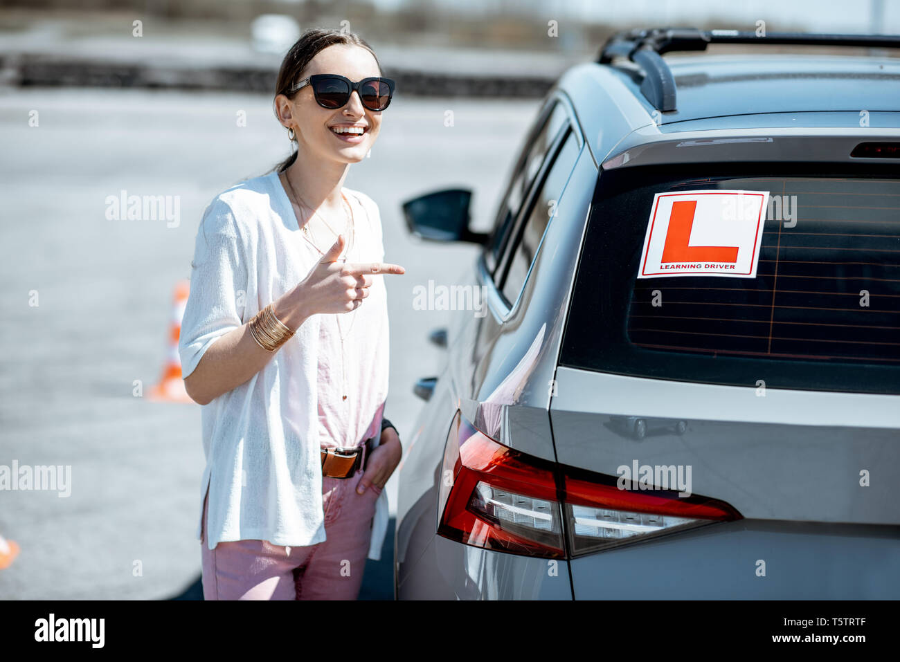Portrait of a young female student standing near the learning car on ...