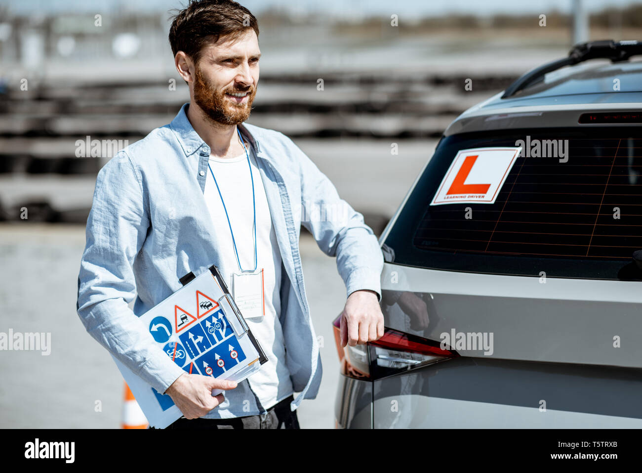 Portrait of a handsome drivers instructor standing with road signs near ...