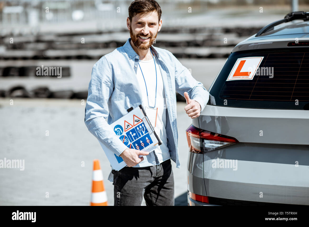 Portrait of a handsome drivers instructor standing with road signs near ...