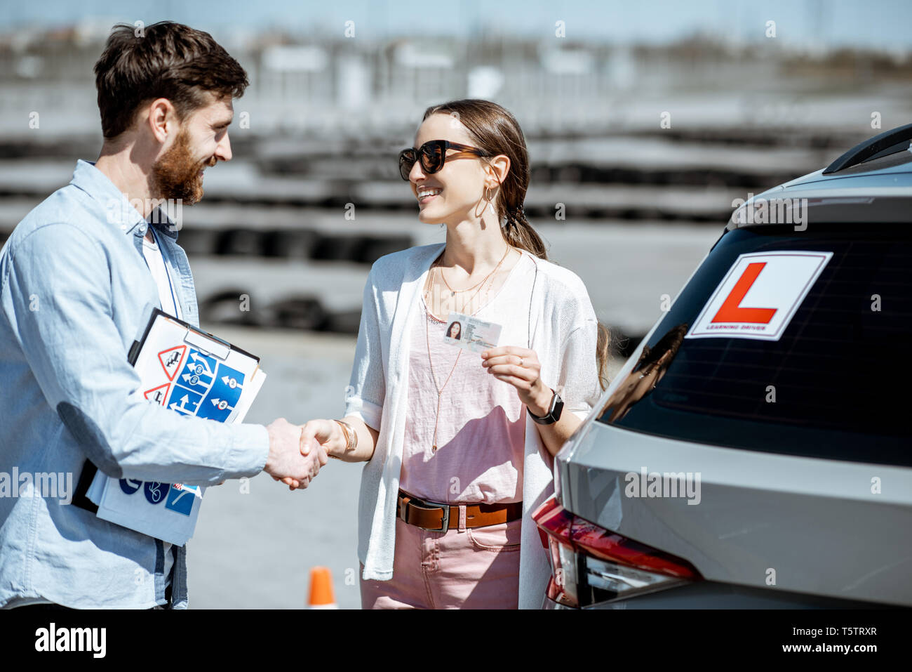 Instructor shaking hands with happy woman getting a driver's license ...