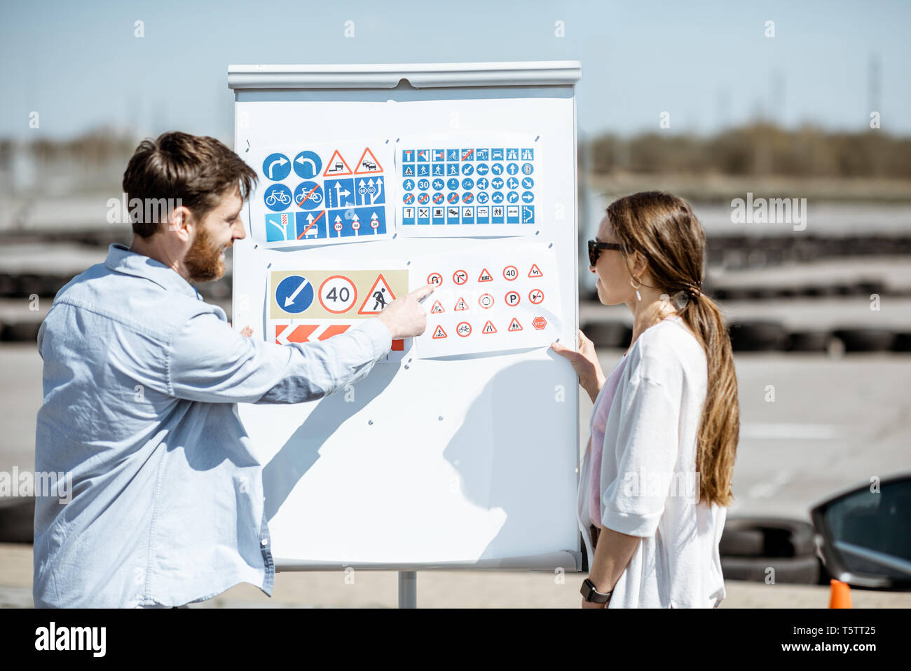 Male instructor showing traffic signs to a young female student ...